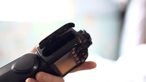 clip-4004792635-man-opens-camera-flash-compartment-carefully-inserts