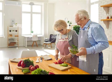 Happy Mature Couple Cooking Healthy Lunch Together In The Kitchen Of Their Modern Apartment