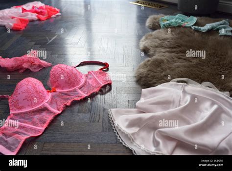 Hot Pink Womans Undergarment Lingerie Strewn On A Blue Stained Oak Floor Of Messy Bedroom Stock