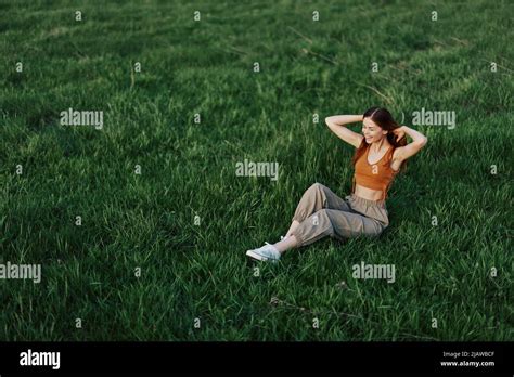 Young Woman Playing Games In The Park On The Green Grass Spreading Her Arms And Legs In