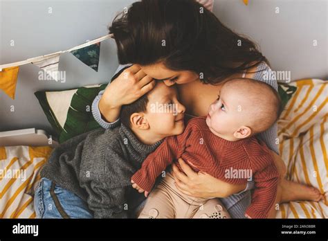 Hermosa Joven Madre Con Sus Hijos En La Cama Perfectamente Abraza A Su Hijo Y Su Pequeña Hija