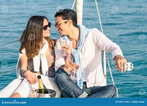 Jeunes Couples Dans Lamour Sur Le Bateau à Voile Avec La Cannelure De Champagne Photo Stock