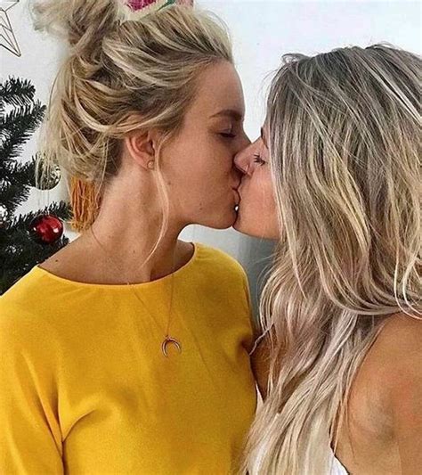 Two Women Kissing Each Other In Front Of A Christmas Tree
