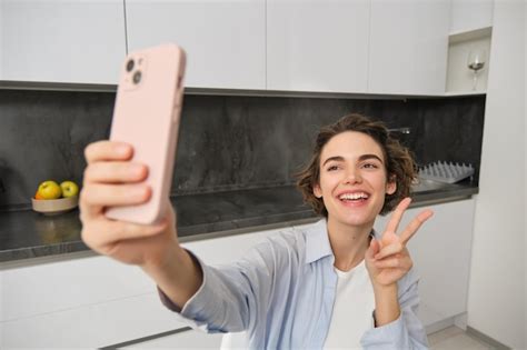 Premium Photo Happy Beautiful Brunette Girl Takes Selfie At Home Poses For Photo With Smartphone