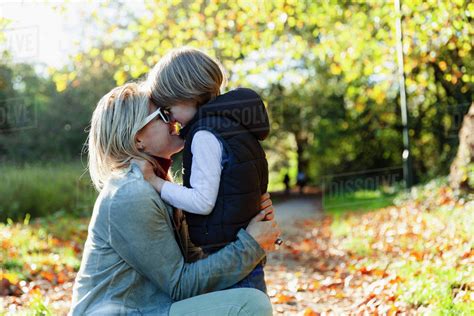 Affectionate Mother And Son Hugging In Sunny Autumn Park Stock Photo