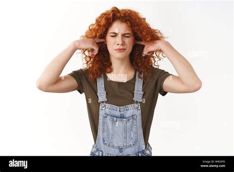 Annoyed And Pissed Curly Haired Ginger Girl Plug Fingers Into Ear Holes Frowning Concerned