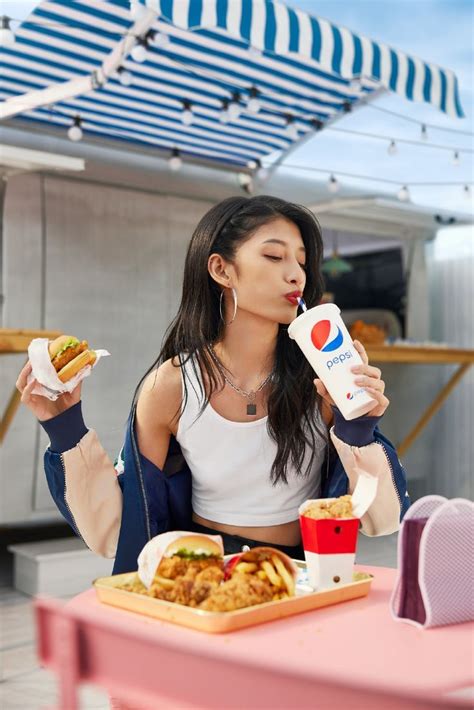 A Woman Sitting At A Table Eating Food And Drinking From A Carton With