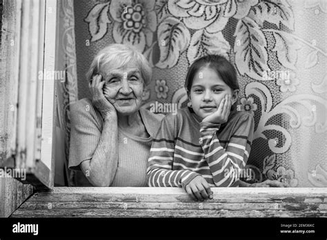 Eine Alte Oma Und Ihre Enkelin Zusammen Um Aus Dem Fenster Zu Schauen Schwarzweiß Foto