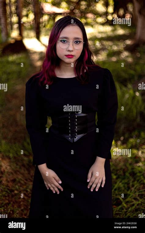 Young Caucasian Dark Haired Girl With Red Streaks In Black Dress Outfit With Corset Belt And