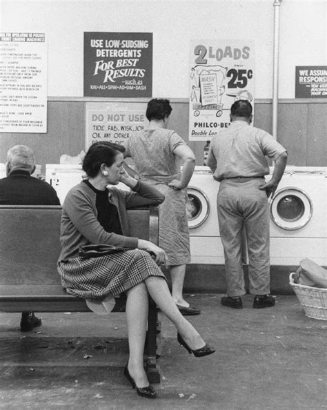 A Woman Sitting On A Bench In Front Of Washers And Dryers With Two Men