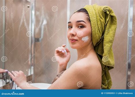 Portrait Of A Young Brunette Woman Applying Cream Or Face Mask In The Bathroom Stock Image