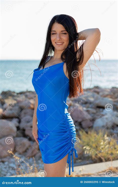 Beautiful Caucasian Girl In Short Blue Dress Posing Outside With Lake In The Background Stock
