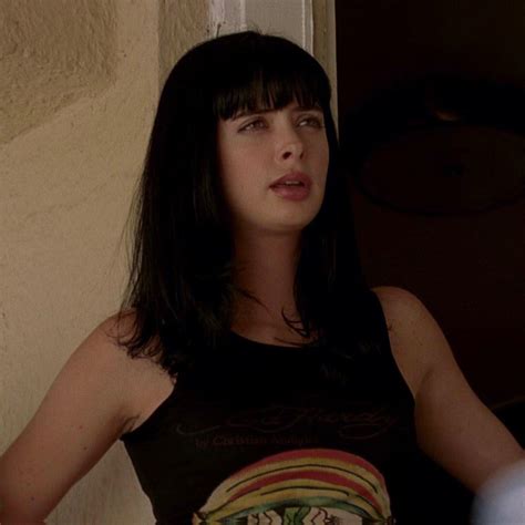 A Woman Standing Next To A Wall With Her Hands On Her Hips And Looking Off Into The Distance
