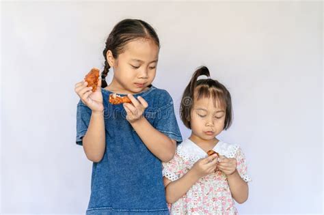 Close Up Portrait Of Two Satisfied Adorable Asian Girls Eating Fried