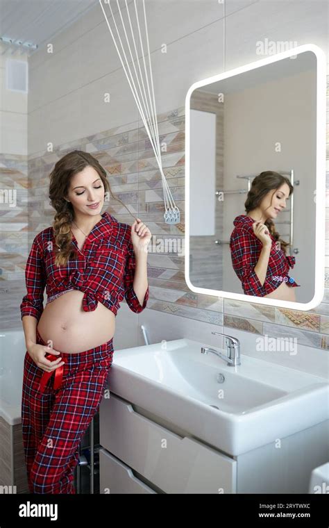 A Pregnant Woman In The Bathroom Female Dressed In Red Pajama And Open Belly Enjoying Her
