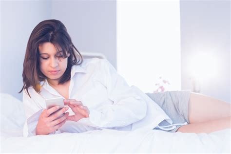 Premium Photo Sexy Brunette Sitting On Her Bed Using Smartphone