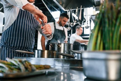Boiling And Adding Ingredients Kitchen Workers Is Together Preparing The Food Stock Image