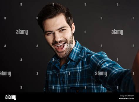 Joyful Handsome Unshaven Guy Smiling While Taking Selfie Isolated Over Black Background Stock