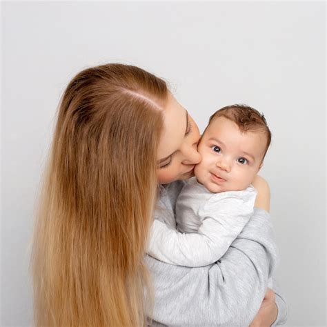 Mamá y bebé juegan en la cama madre e hijo familia feliz hermosa niña