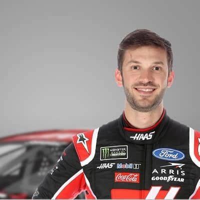 A Man Standing In Front Of A Race Car
