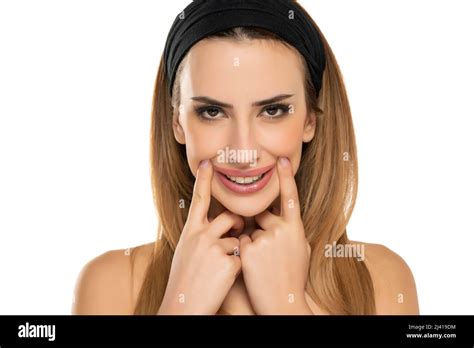 Portrait Of Young Woman Stretching Mouth In Fake Smile With Her Fingers On White Background