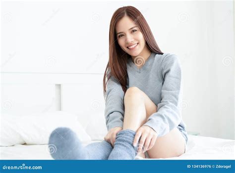 Young Pretty Brunette Girl Putting Warm Sock Sitting In Bed On Cold Winter Day Lifestyle People