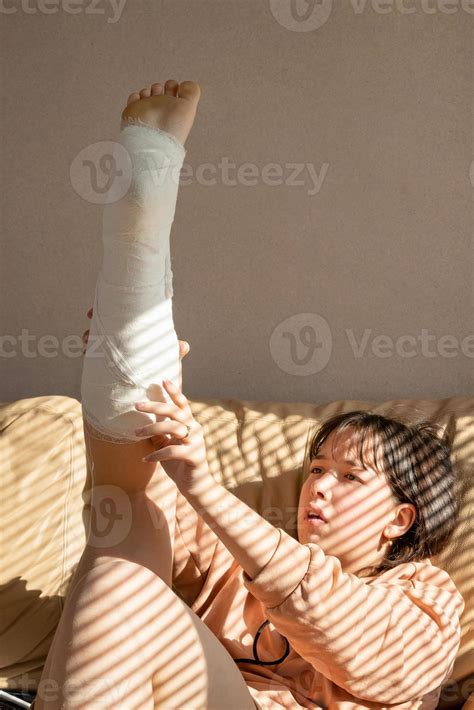 Chica Con Una Expresión De Dolor En La Cara Yace En El Sofá Con La Pierna Levantada Enyesada