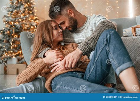 Laying Down On The Sofa And Embracing Lovely Young Couple Are Celebrating New Year At Home