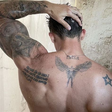 A Man Has Tattoos On His Back And Is Holding His Head Up To His Hair